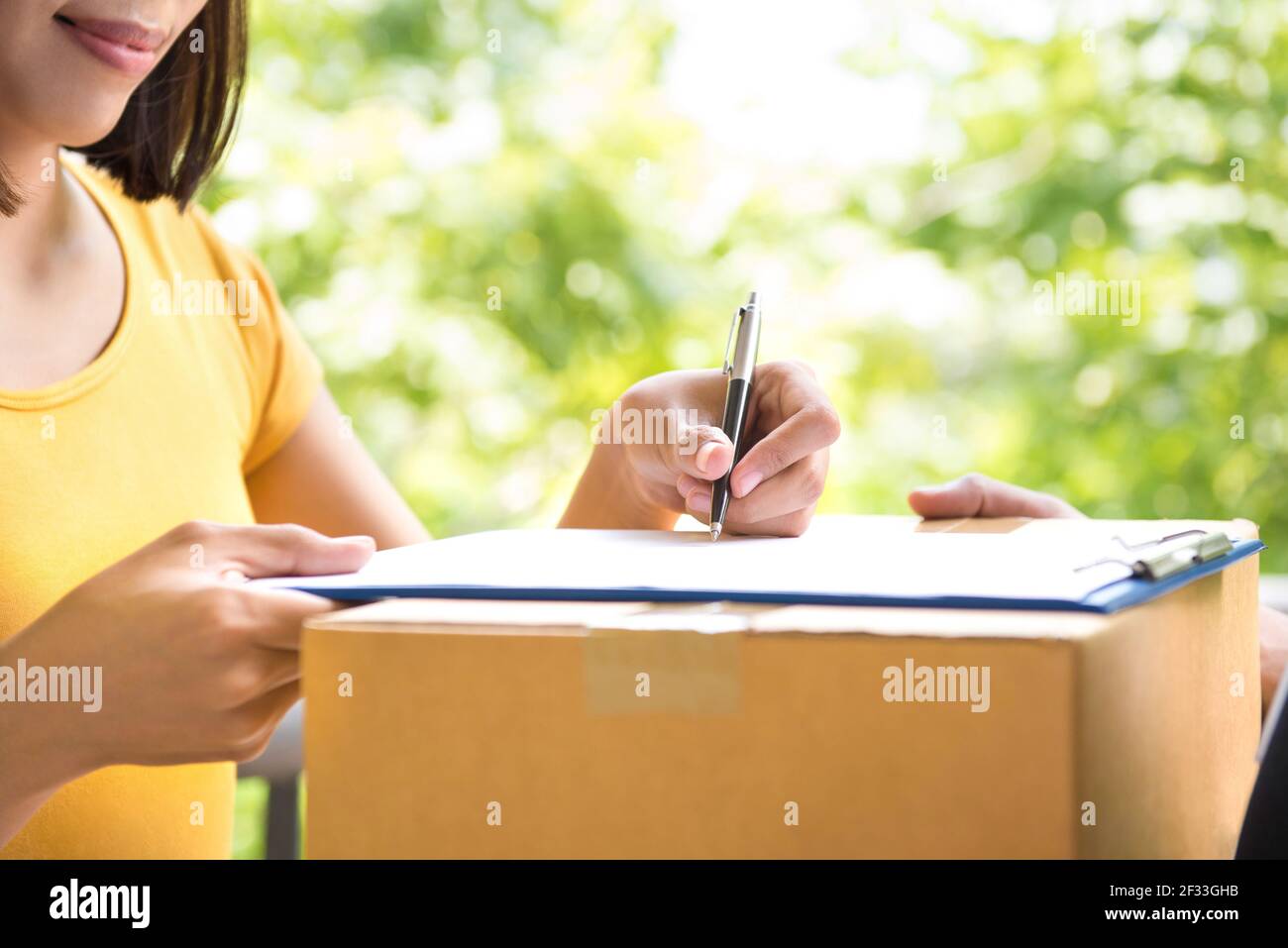 Young woman signing document receiving package from delivery man ...