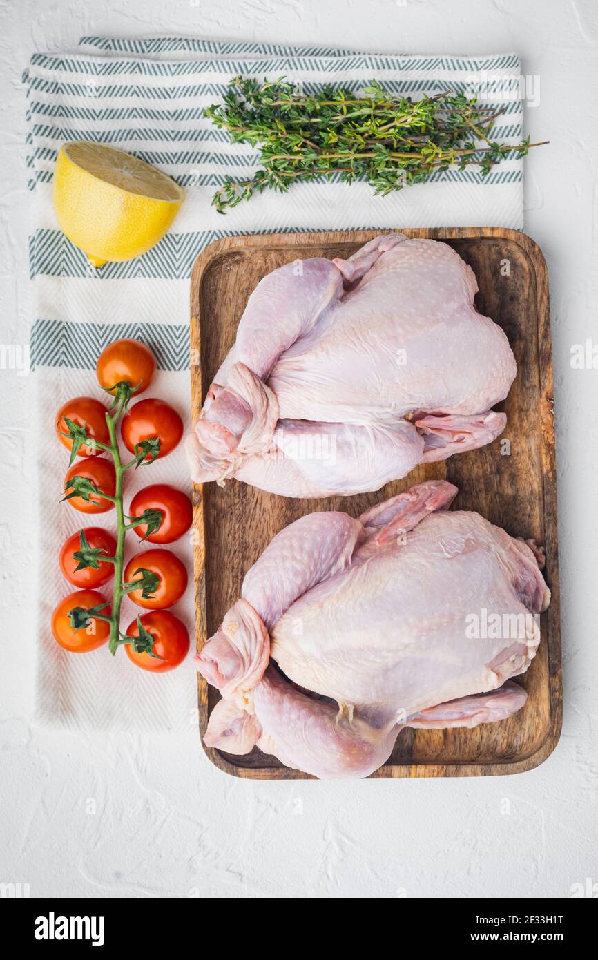 Raw small young whole chicken with herbs and ingredients, on white ...