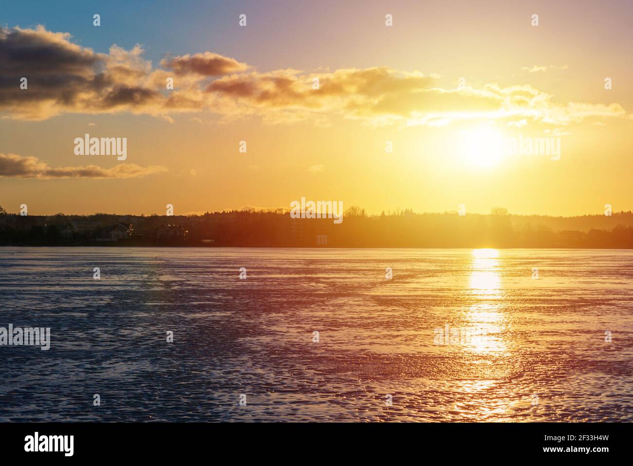 Winter landscape with frozen lake at sunrise or sunset. Lake glistening ...