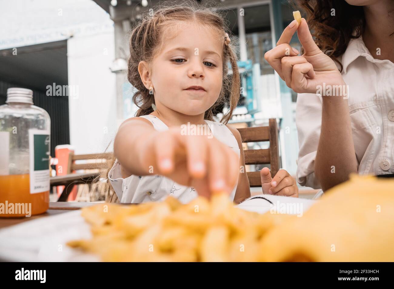 Mom and daughter eat french fries at an outdoor cafe Stock Photo - Alamy
