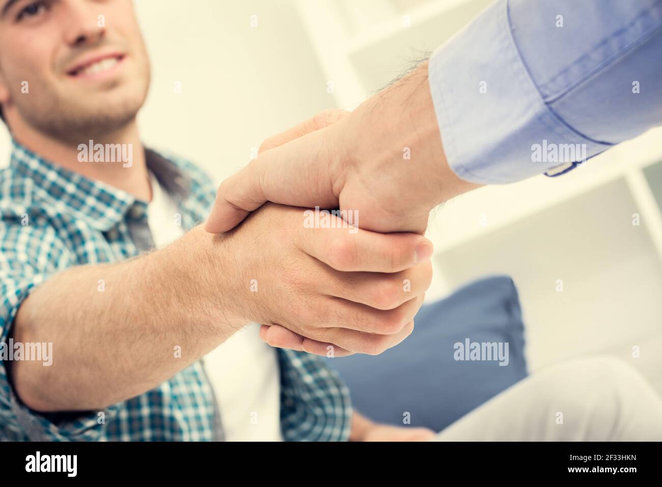 Men in casual clothes making handsdhake in living room Stock Photo - Alamy
