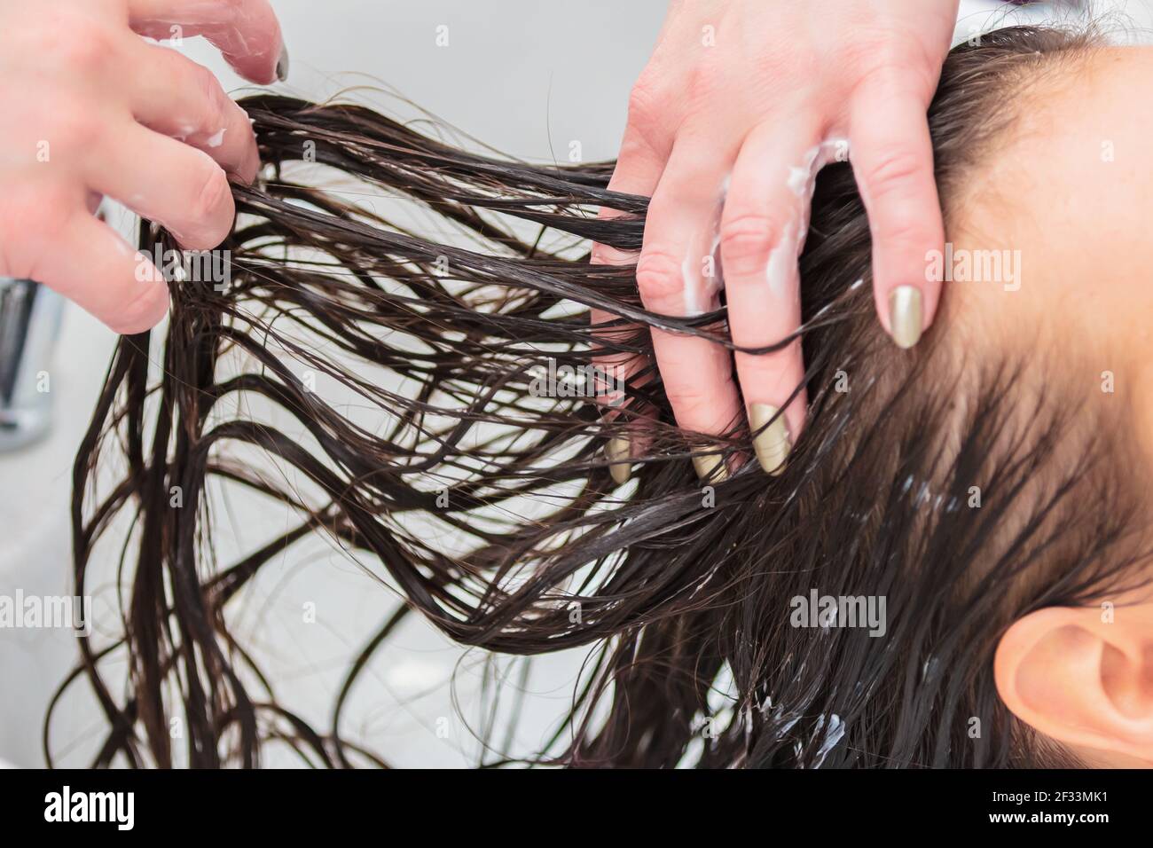 The hairdresser washes the head of a girl with long hair in the sink ...