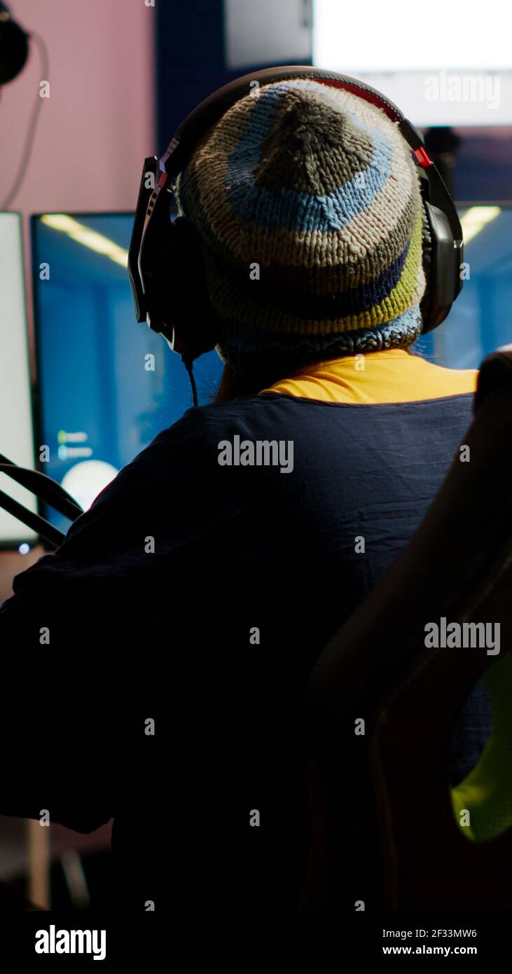 Back shot of pro gamer woman playing first person video games using RGB ...