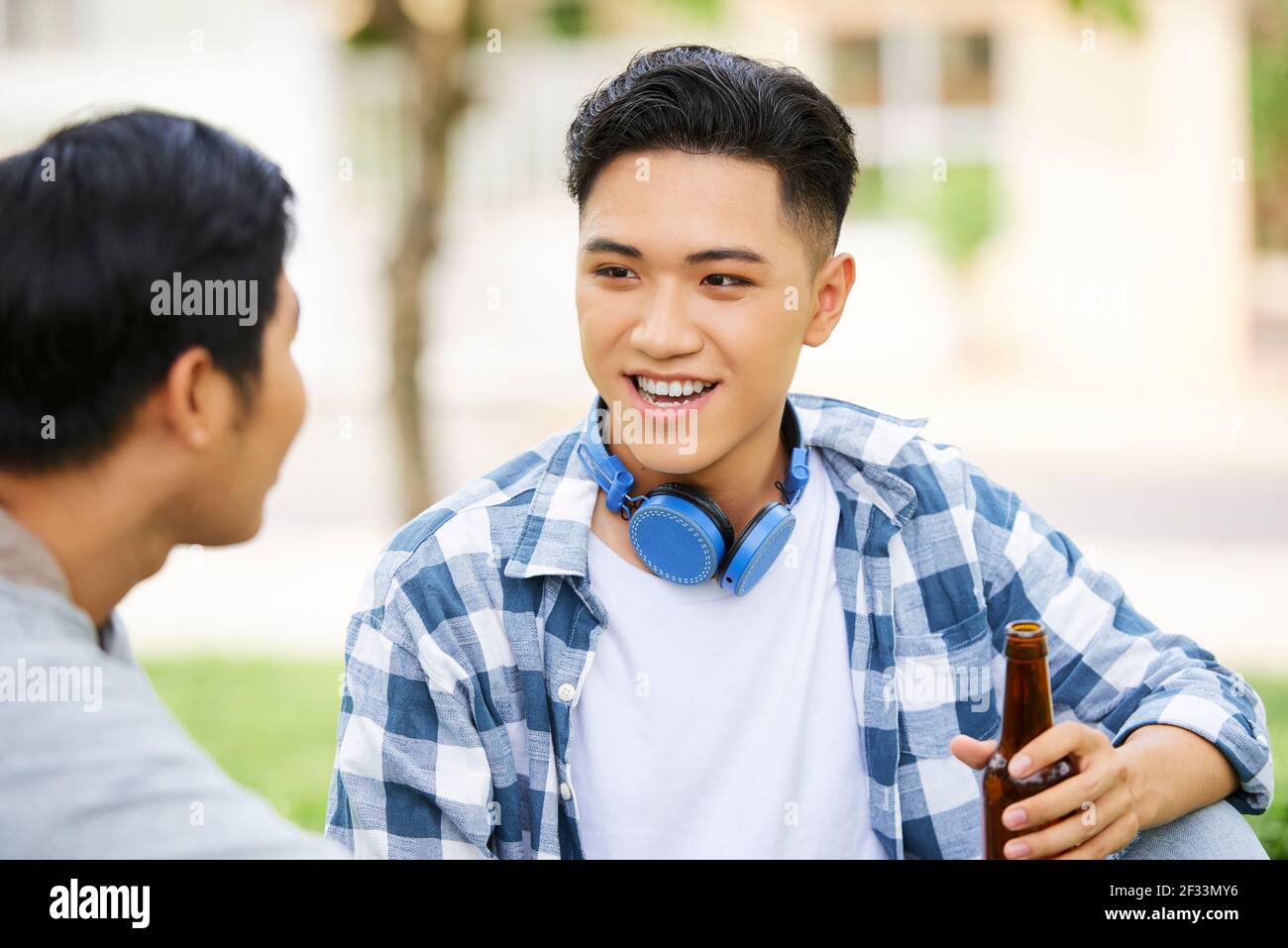 Two friends talking to each other and drinking beer outdoors Stock ...