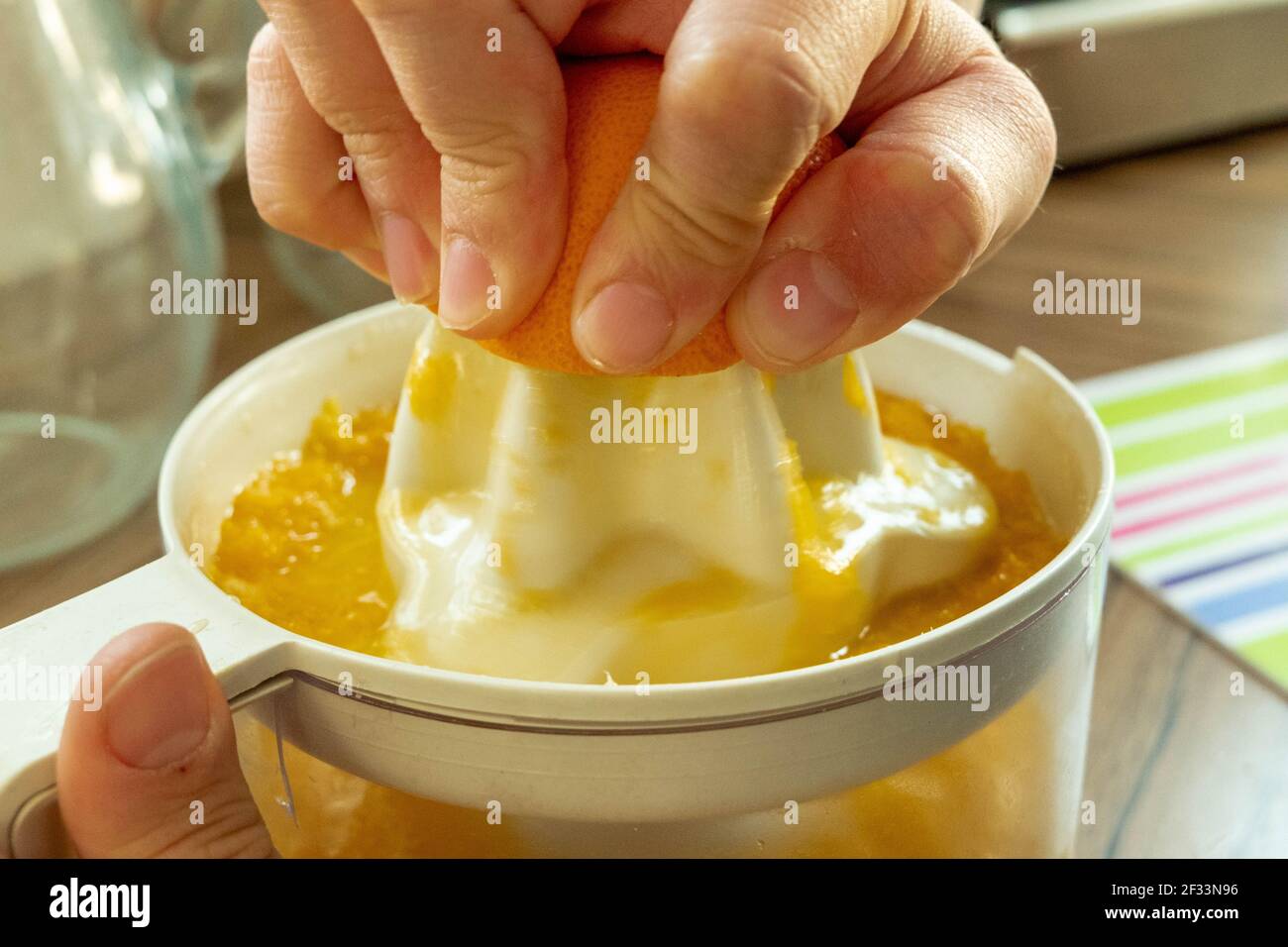 Hand squeezing oranges fresh on the orange press with pulp Stock Photo ...