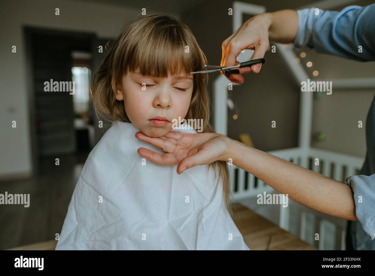 Close-up of female mother's hands cutting hair of her four years old ...