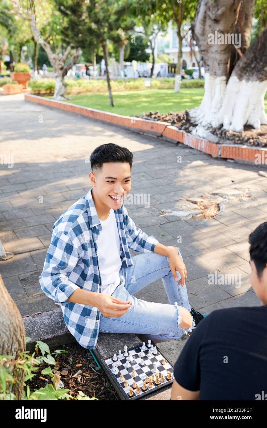 Asian young man playing chess together with his friend on the street ...