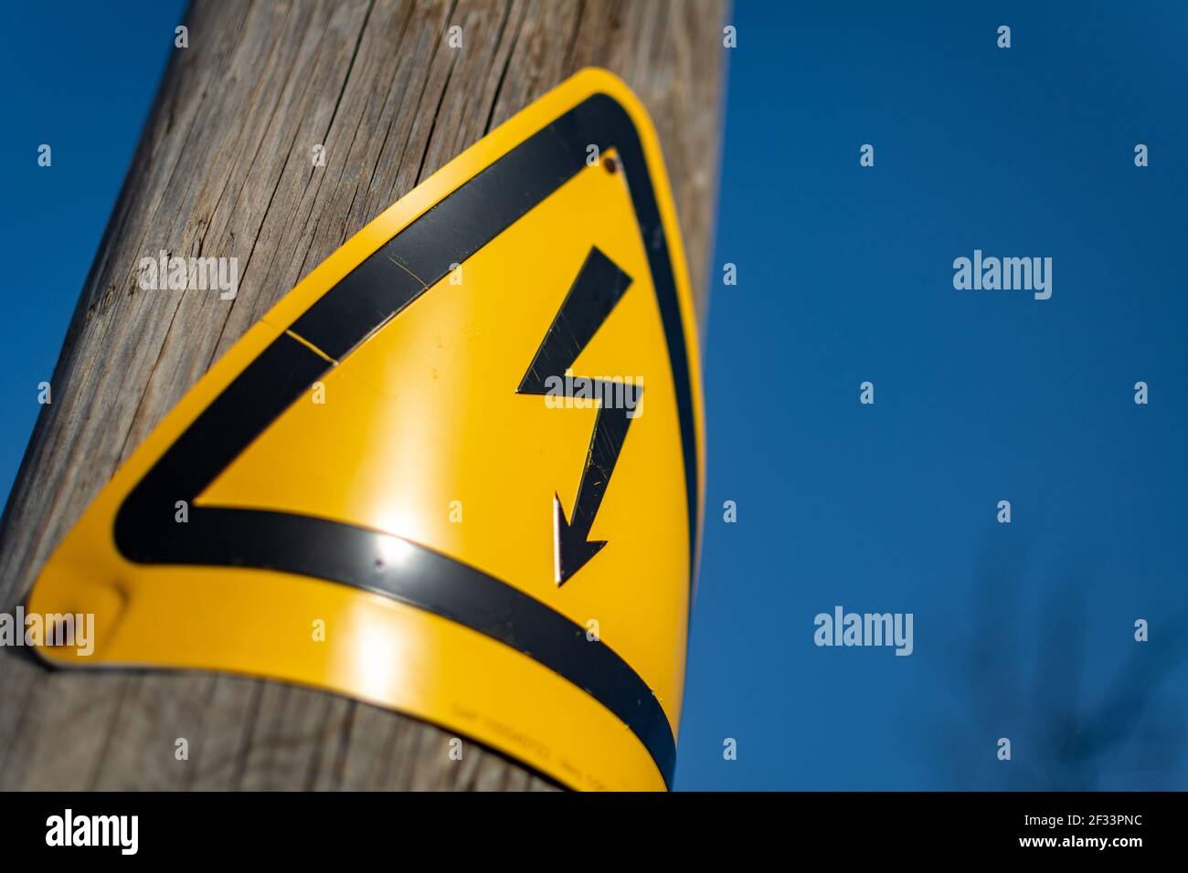 Sign at the bottom of a wooden electrical pole warning of the danger of ...