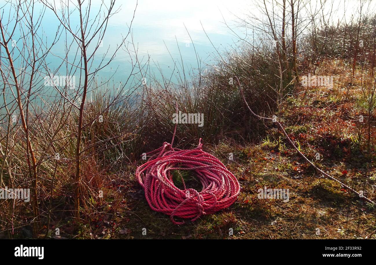 Roll of red rope on the bank. The lake has light blue water. It's a ...