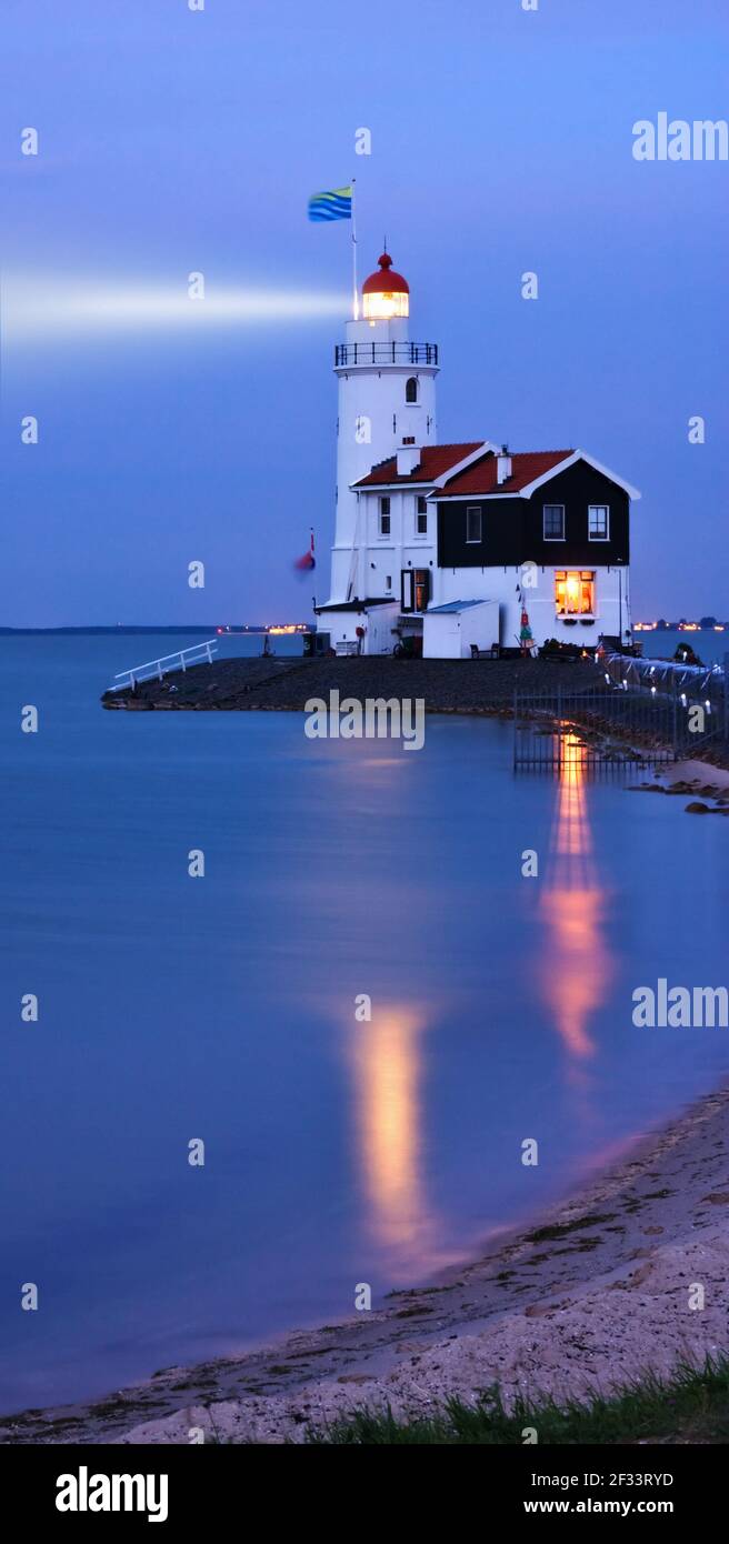 illuminated lighthouse in twilight, light beam shines in dark skies ...