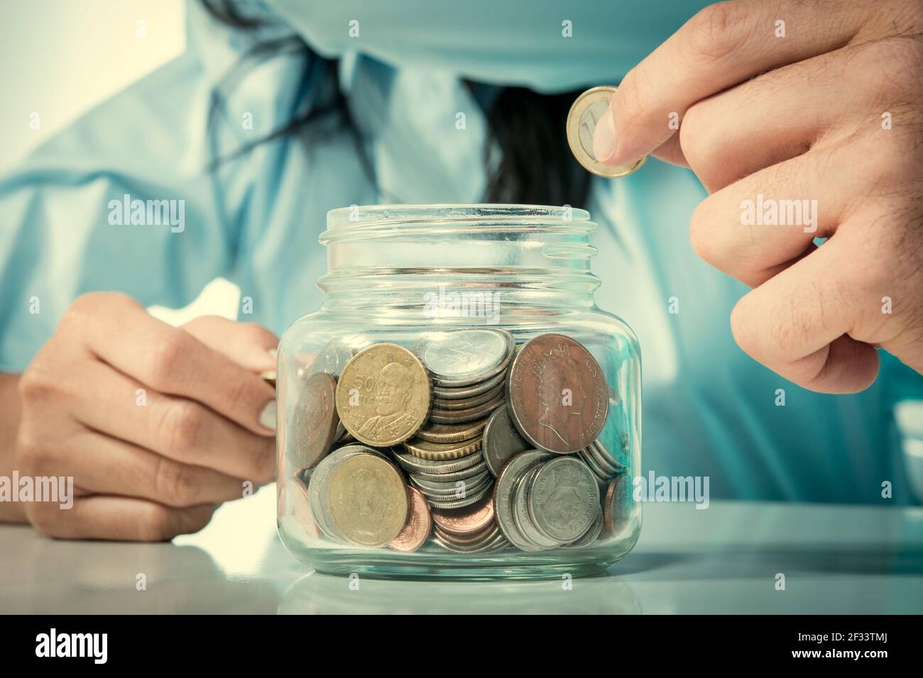 Hand putting money (coin) in the glass jar - savings concept Stock ...