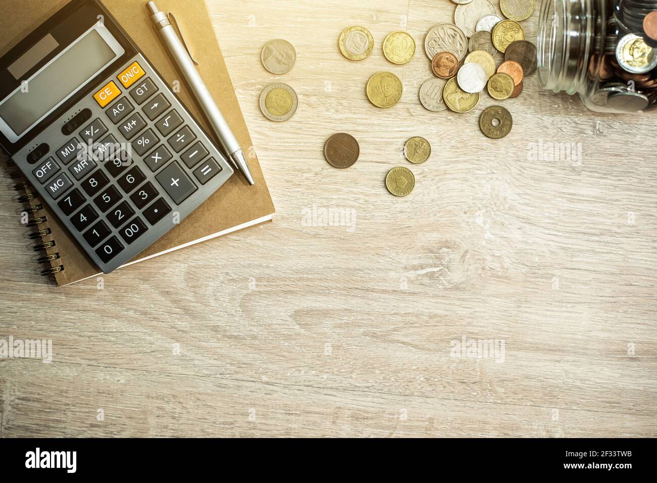Money (coins), calculator and some stationery on wood table, top view with copy space ...