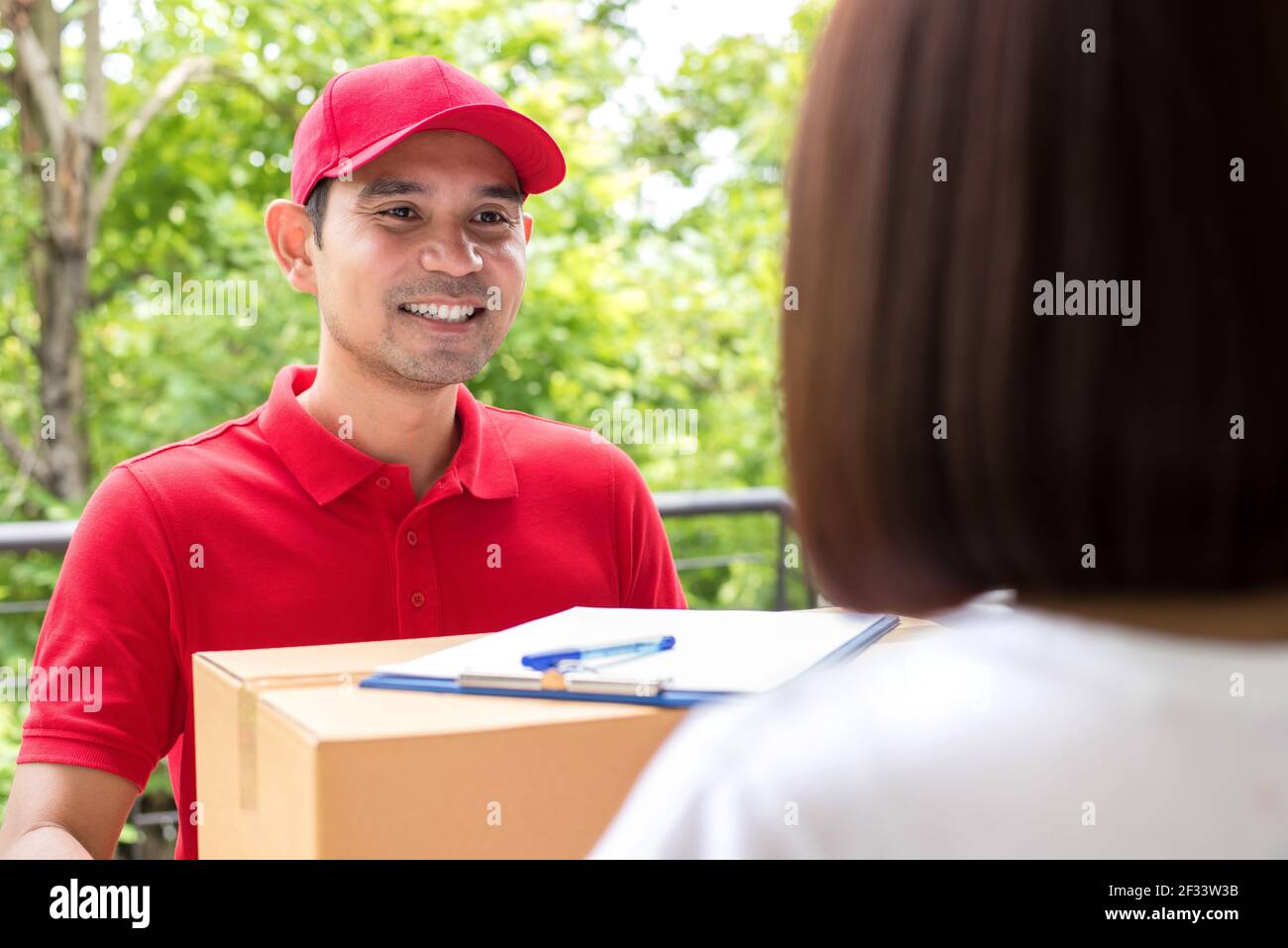 Smiling delivery man delivering parcel to a woman Stock Photo - Alamy