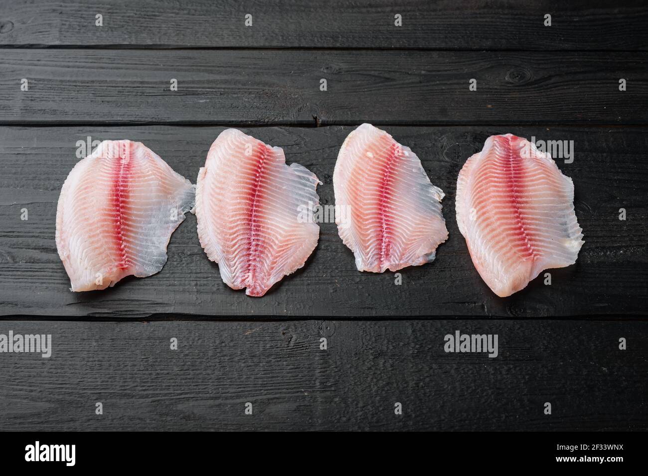 Tilapia fish fillet meat cuts, on black wooden table, top view Stock ...