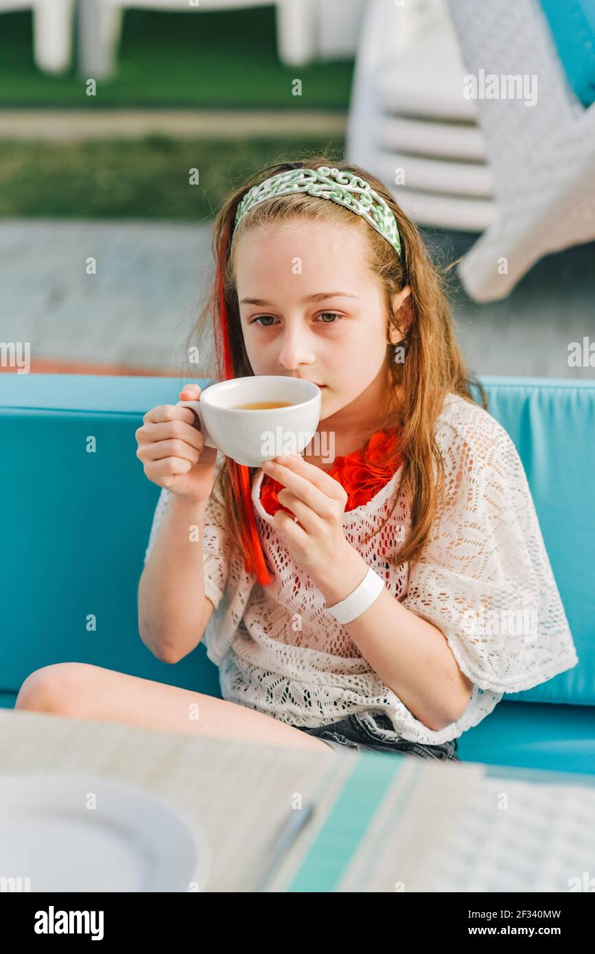 Teenage girl is drinking tea. Teenage girl in a summer cafe. Summer ...