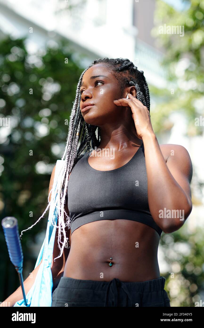 Portrait of pretty strong young Black woman with braided hair walking ...
