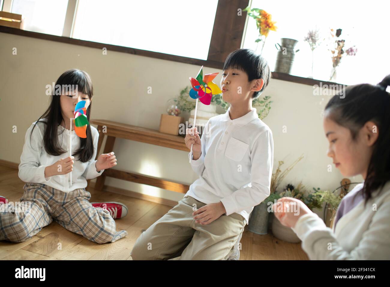 Boy and Girl Blowing Pinwheel Stock Photo - Alamy