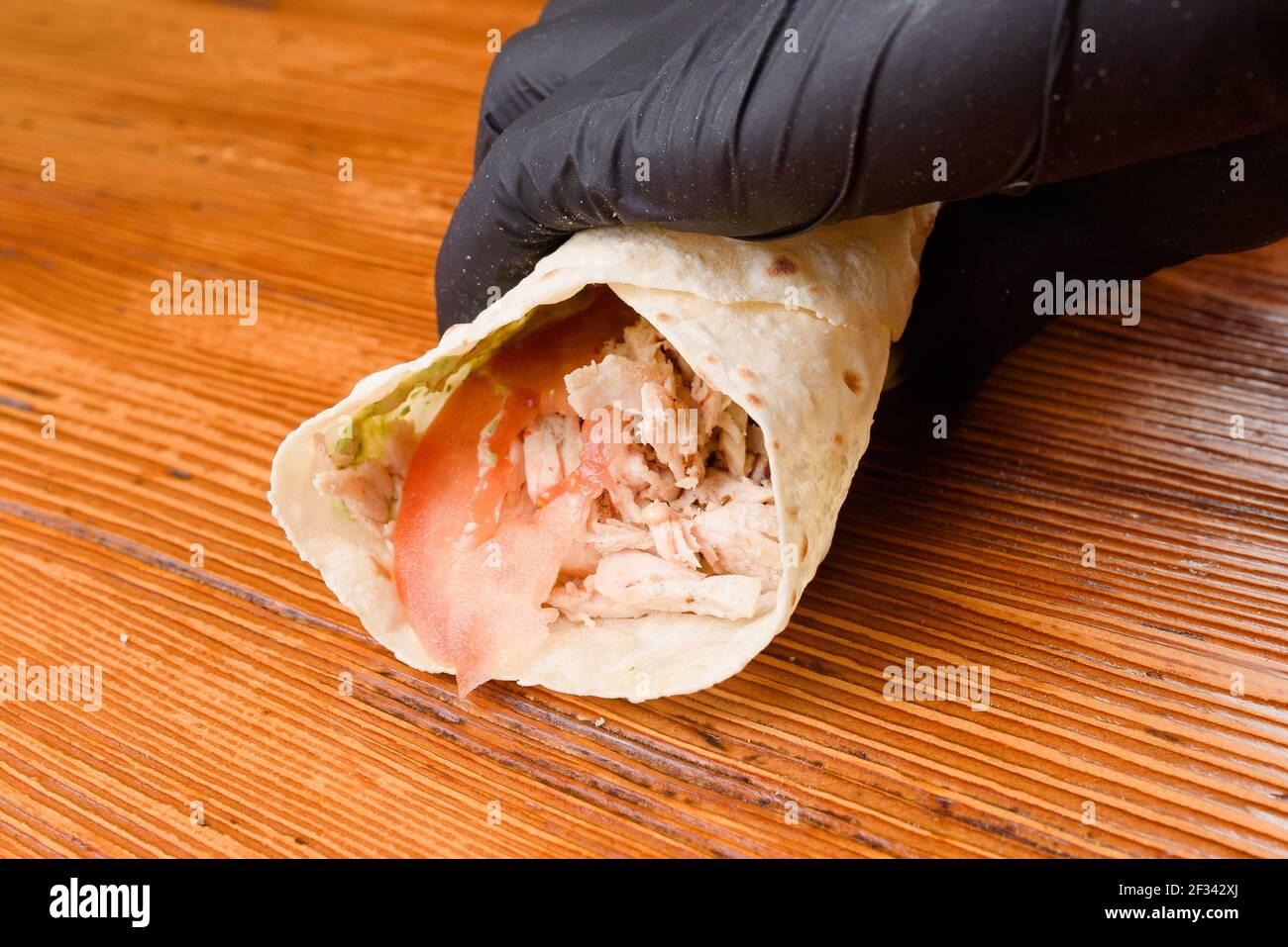 Burrito making process. The chef wraps stuffed pita on a wooden table ...