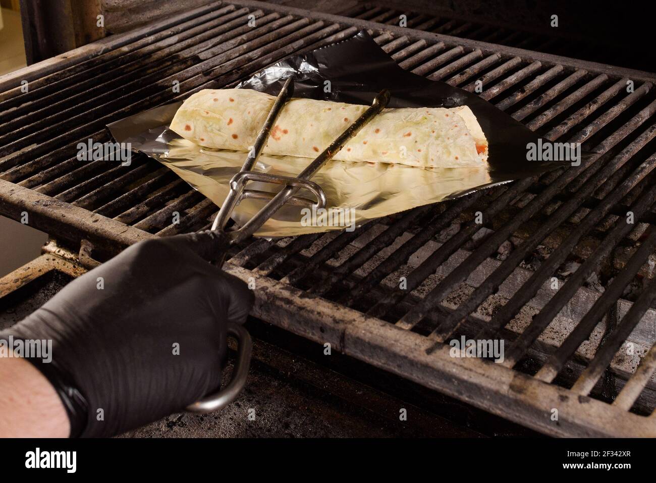 The process of making a foil grilled burrito. Mexican dish Stock Photo ...