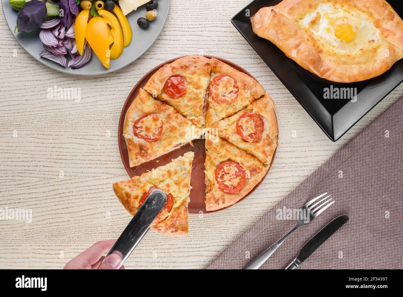 Khachapuri with cheese and tomatoes, egg, slices of vegetables, basil ...