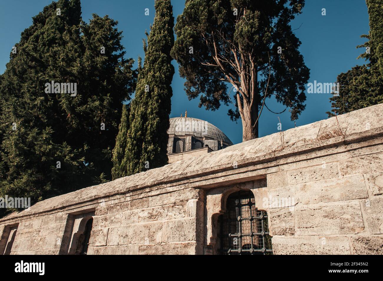 stone wall with fenced windows, and high trees near Mihrimah Sultan ...