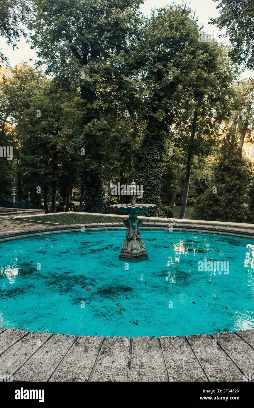 decorated fountain with blue water in green park Stock Photo - Alamy