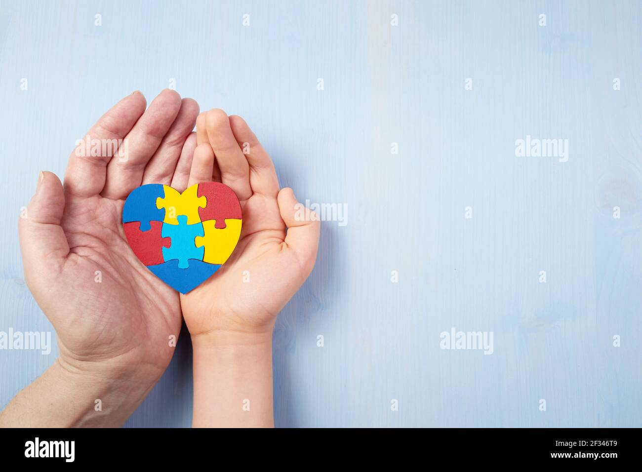 Father and autistic son hands holding jigsaw puzzle heart shape. Autism ...