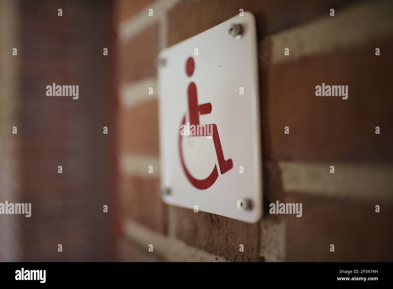 a handicap sign hanging on building wall Stock Photo - Alamy