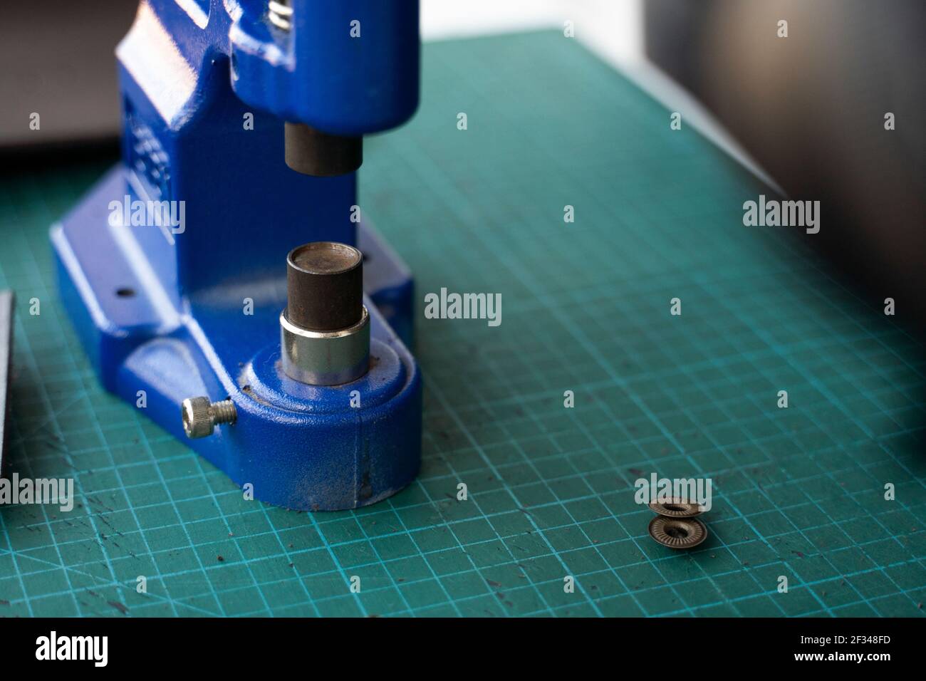 Artisan using hand press for setting snaps in leather for makes a ...