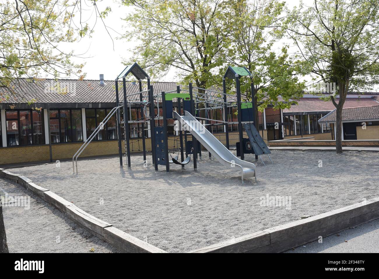 A small playground with a slide and swings Stock Photo - Alamy