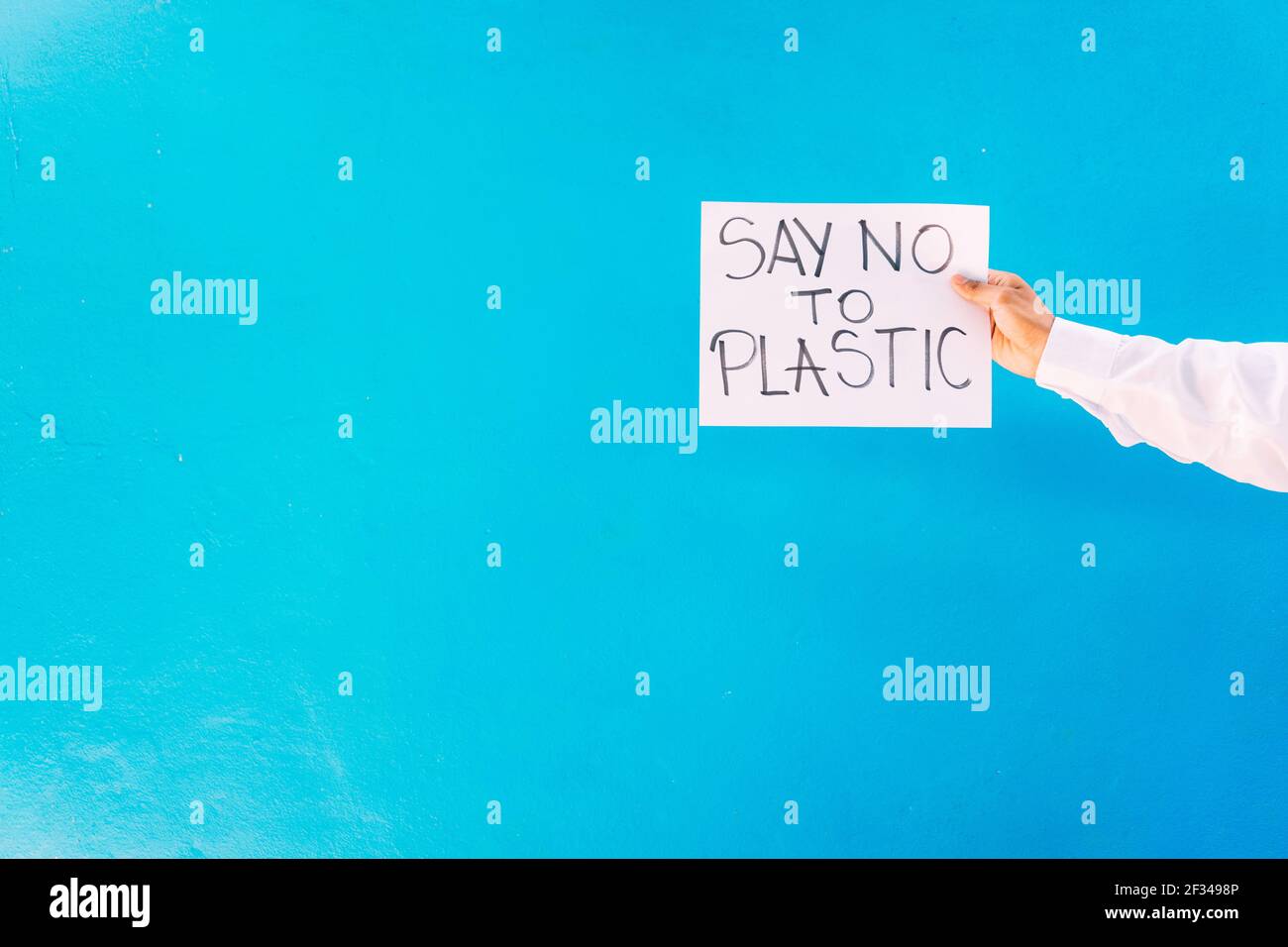 A female hand holding a paper with the writing "say no to plastic" on ...