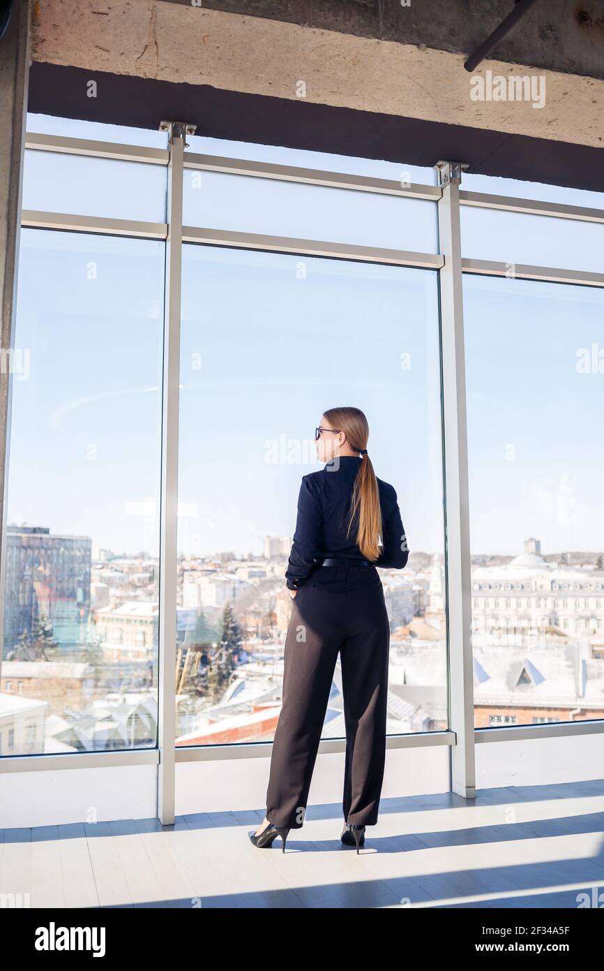 Confident business woman boss standing in modern office or hotel window ...
