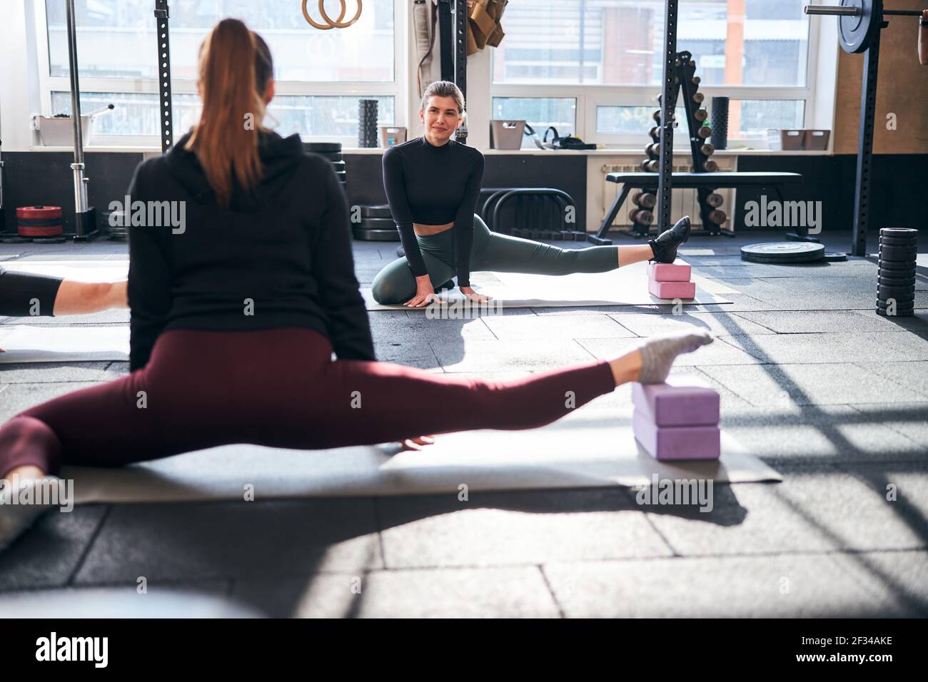 Two young ladies stretching leg muscles before doing splits Stock Photo ...