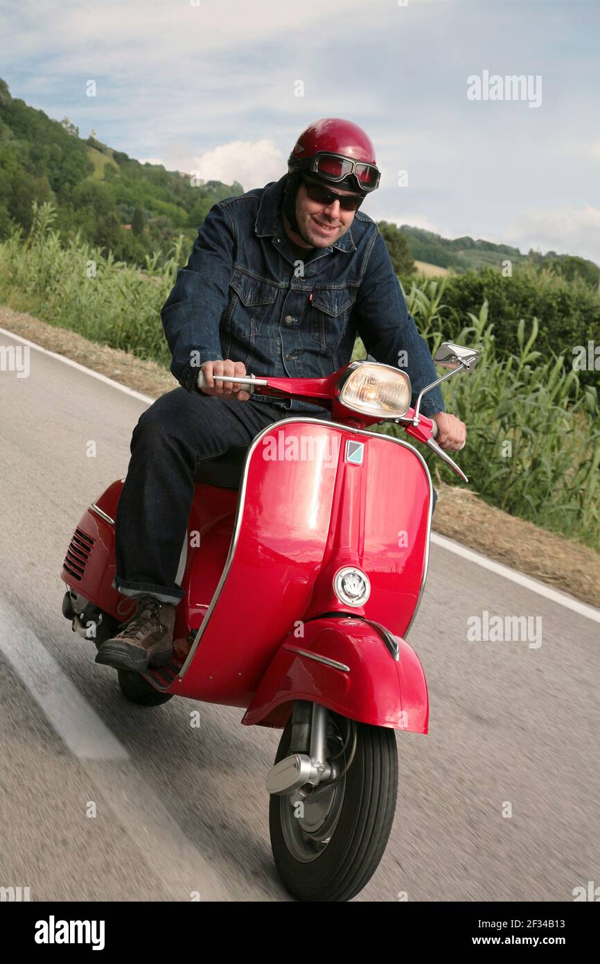 Man riding red motor scooter in Tuscan countryside Stock Photo - Alamy