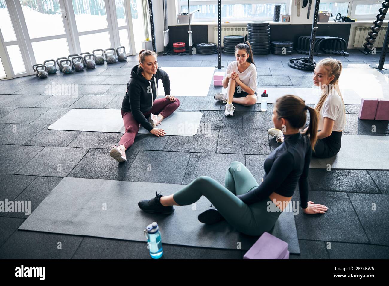 Athletic young ladies discussing workout plan on gym floor Stock Photo ...