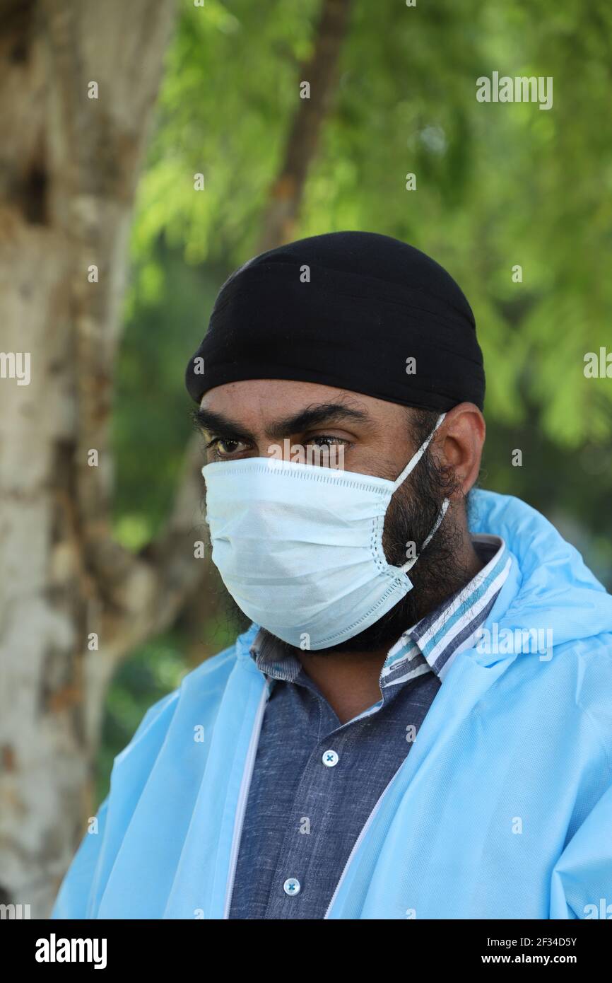A middle-aged Indian man with a turban and mask, wearing a scrub ...