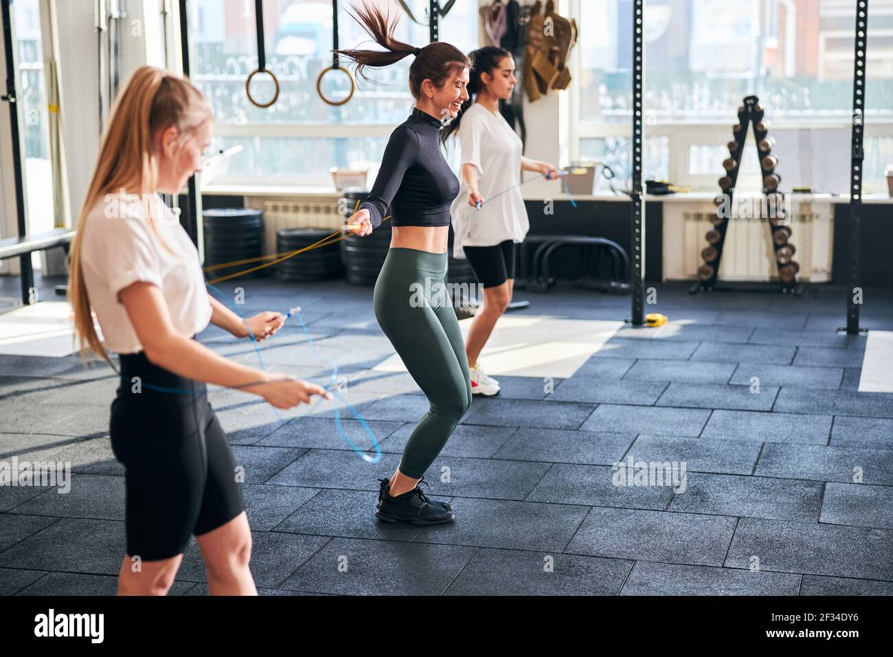 Excited young ladies staying in shape and using skipping ropes Stock ...