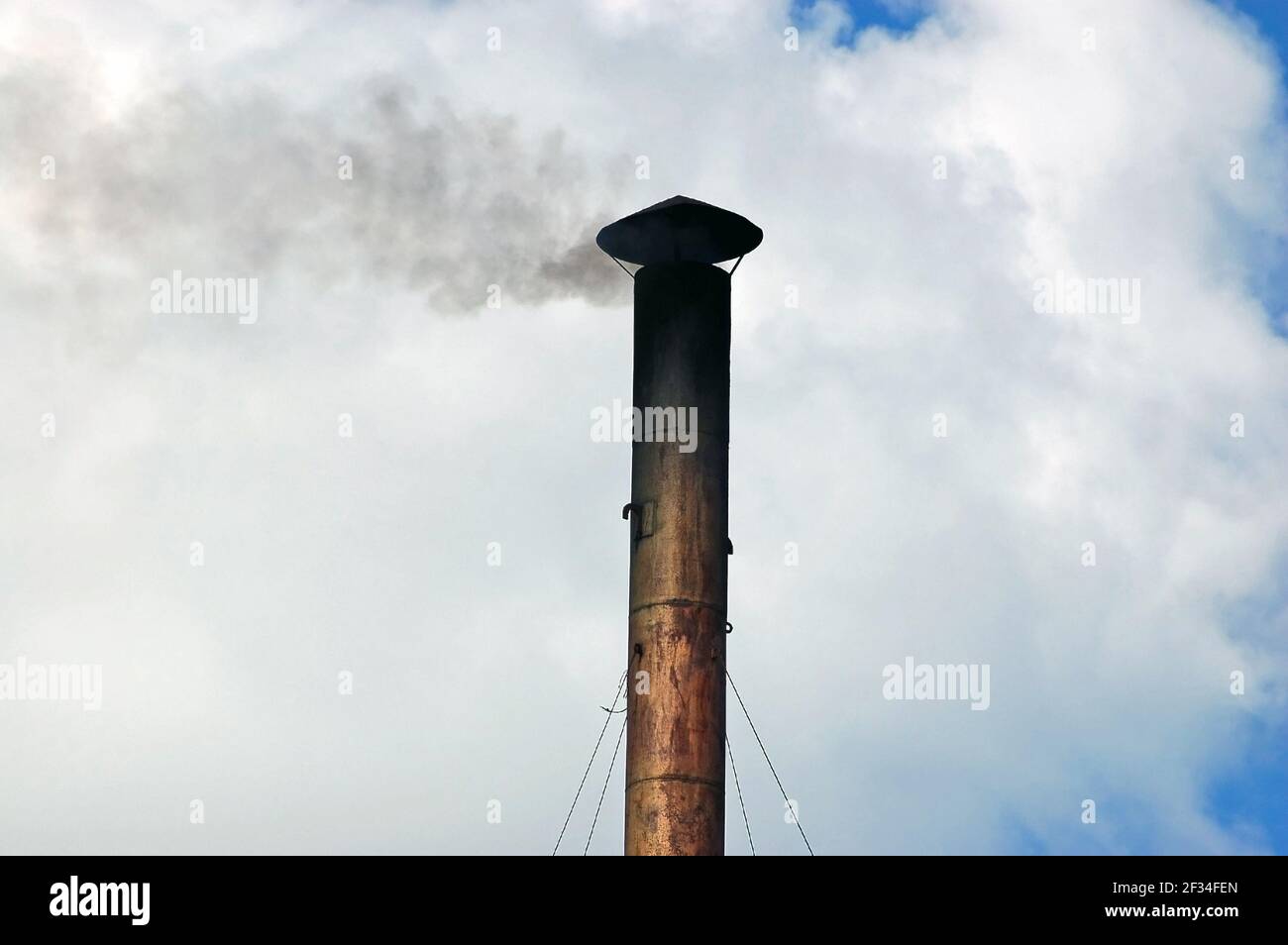A metal chimney covered in soot with smoke pooring out sideways Stock ...
