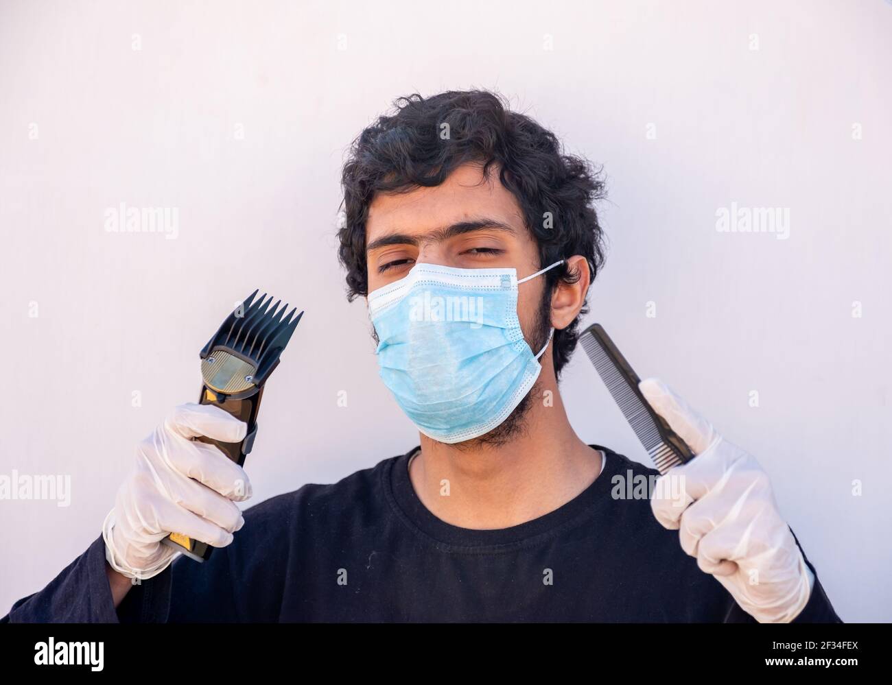 Arabic muslim guy wearing mask and holding barber equipment Stock Photo ...