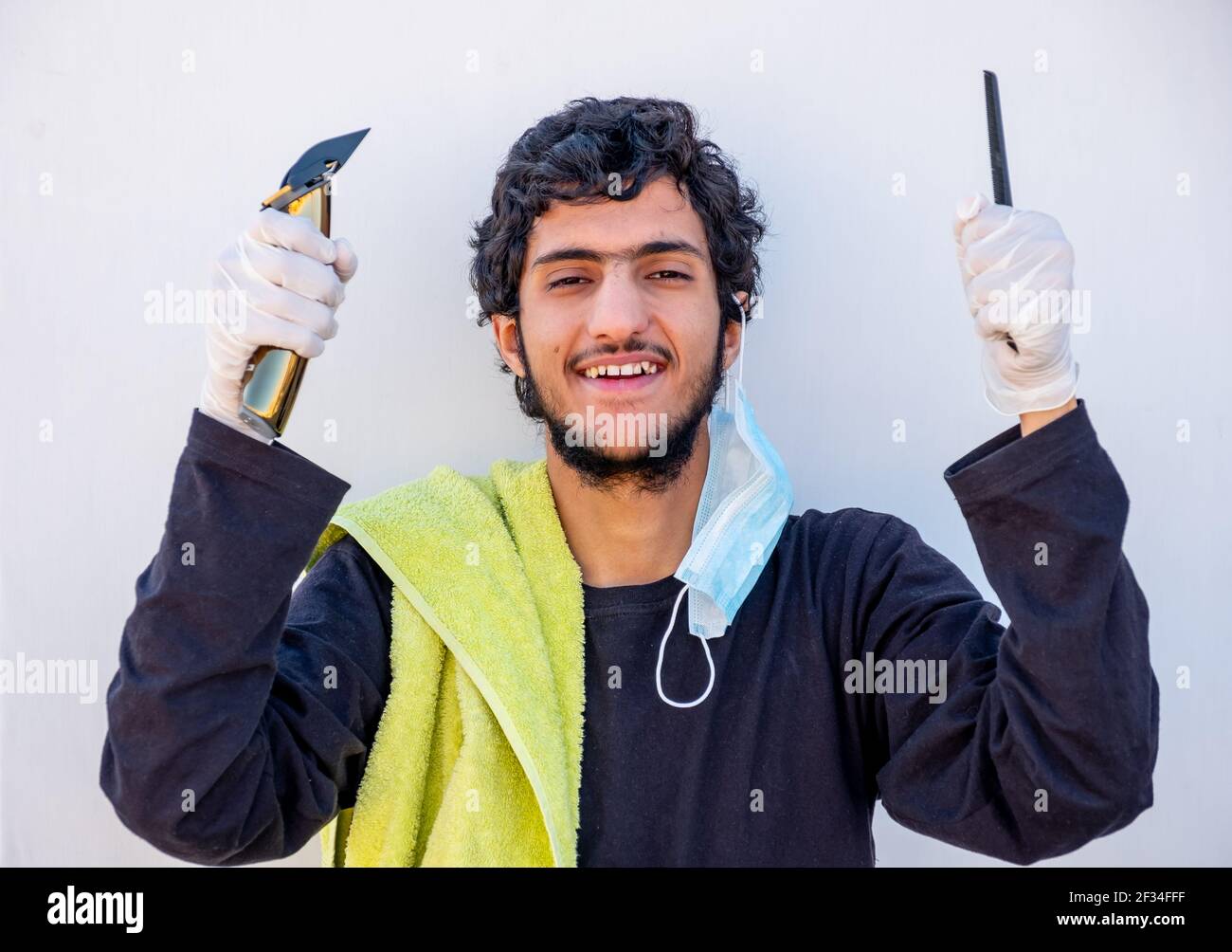 Arabic Muslim guy wearing mask and holding barber equipment Stock Photo ...