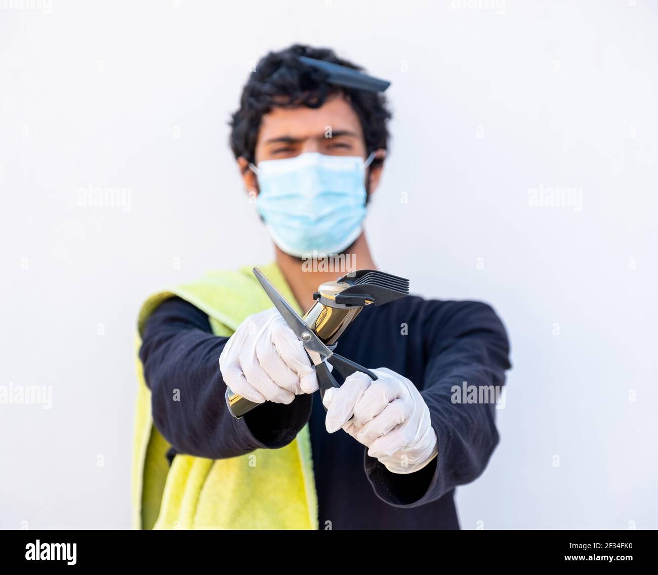 Arabic Muslim guy wearing mask and holding barber equipment Stock Photo ...