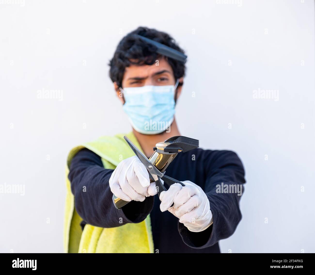 Arabic Muslim guy wearing mask and holding barber equipment Stock Photo ...