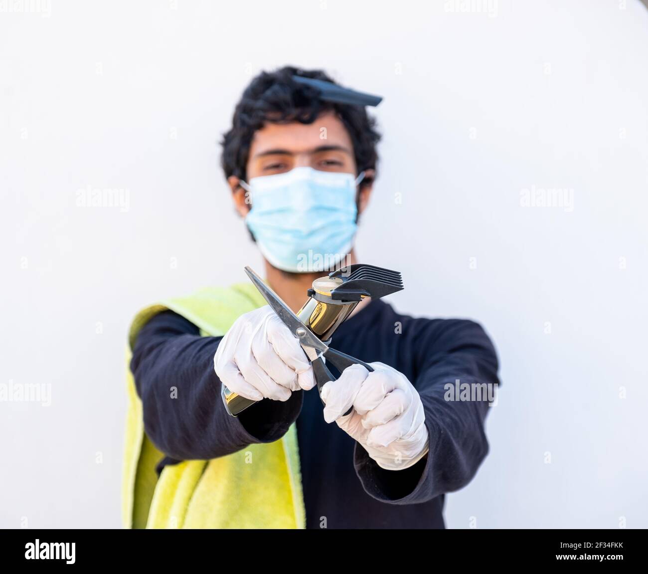 Arabic Muslim guy wearing mask and holding barber equipment Stock Photo ...