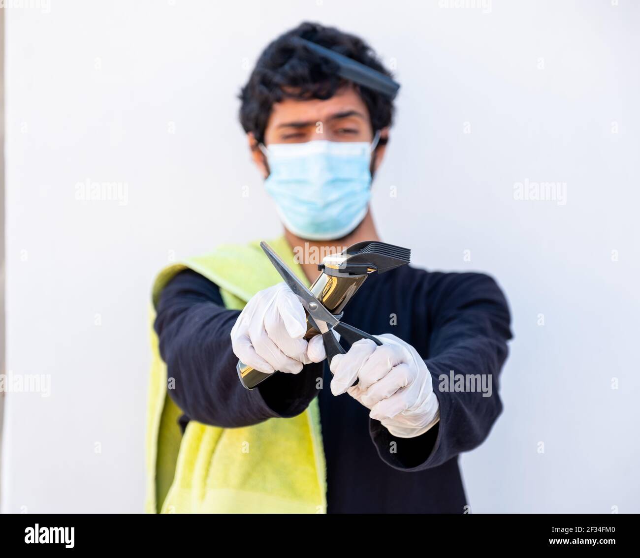 Arabic Muslim guy wearing mask and holding barber equipment Stock Photo ...