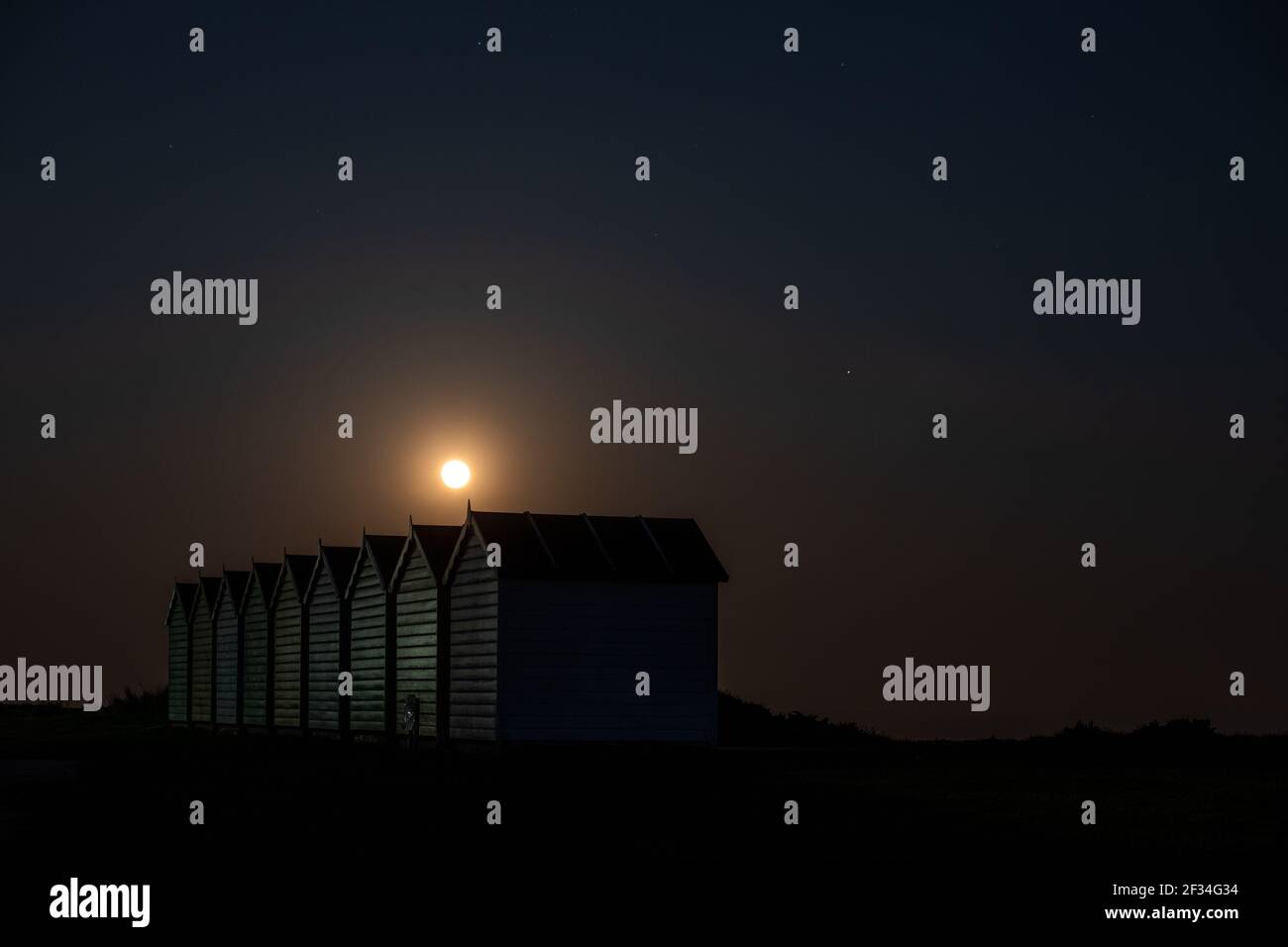 The rising moon seen above beach huts in Rustington, West Sussex Stock ...