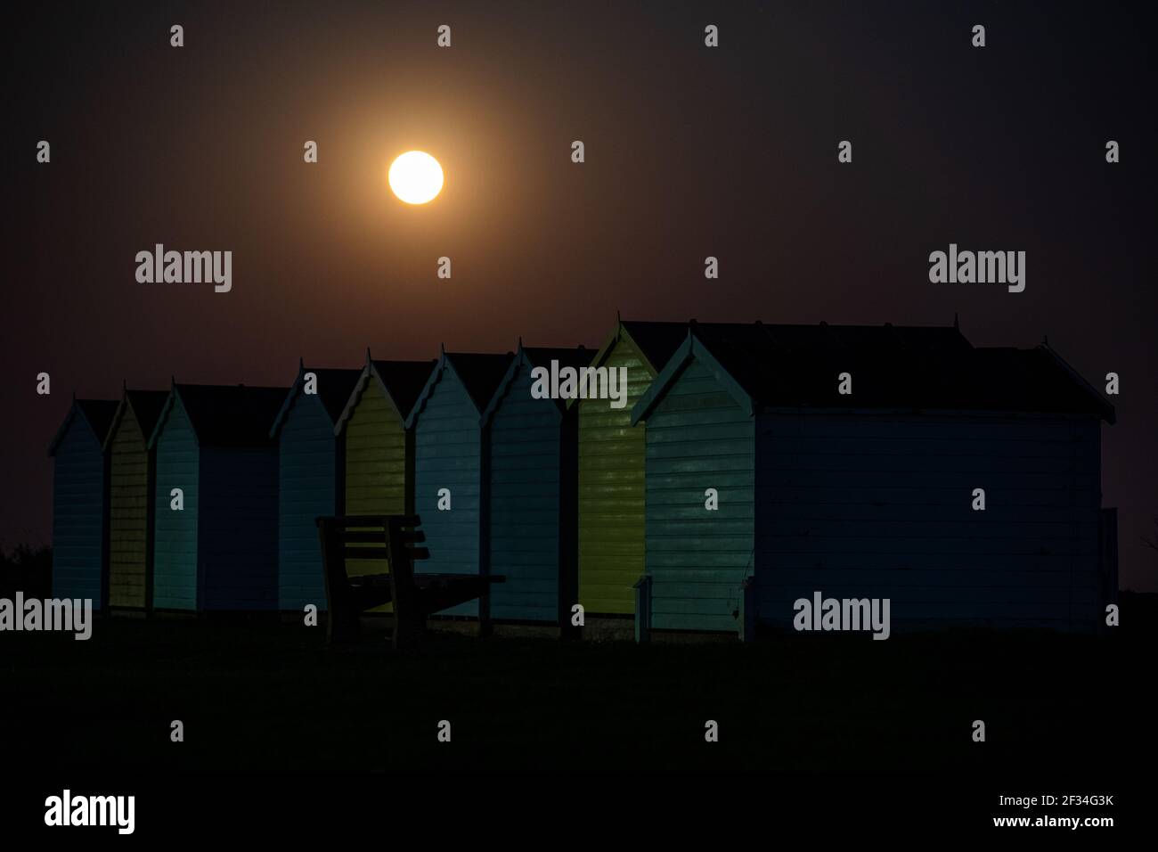 The rising moon seen above beach huts in Rustington, West Sussex Stock ...