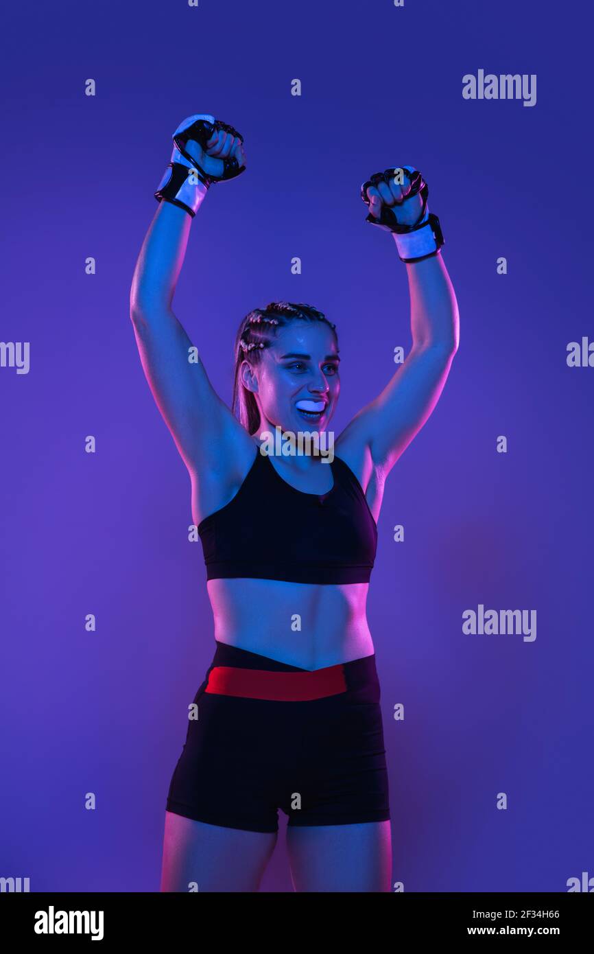 Young female MMA fighter posing isolated over blue-pink background in ...