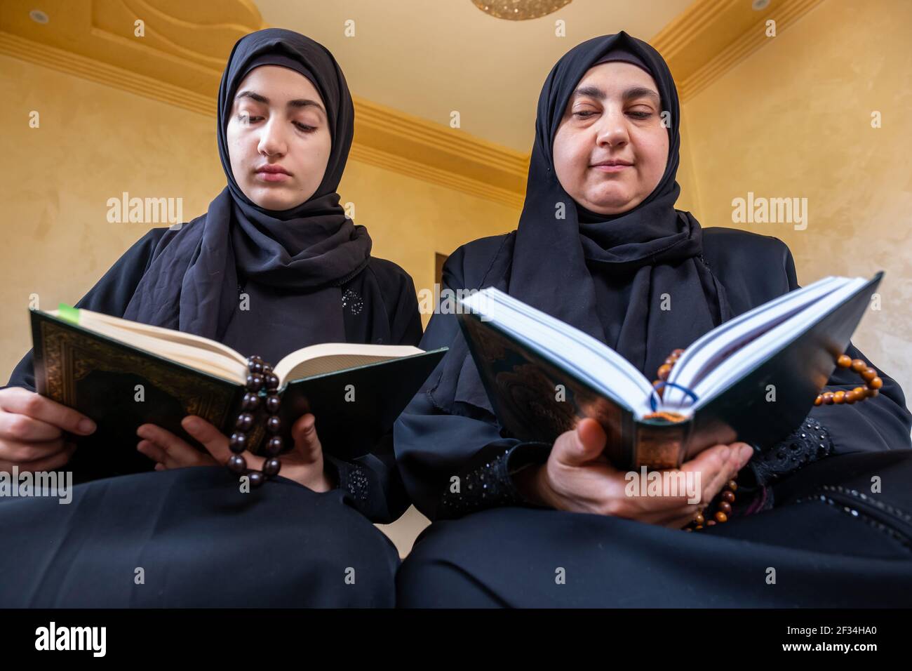 Muslim mother and her daughtersitting togther reading holy book Stock ...