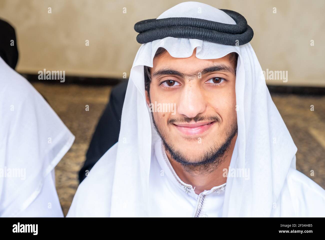 Muslim guy wearing Arabic clothes sitting with his family reading Quran ...