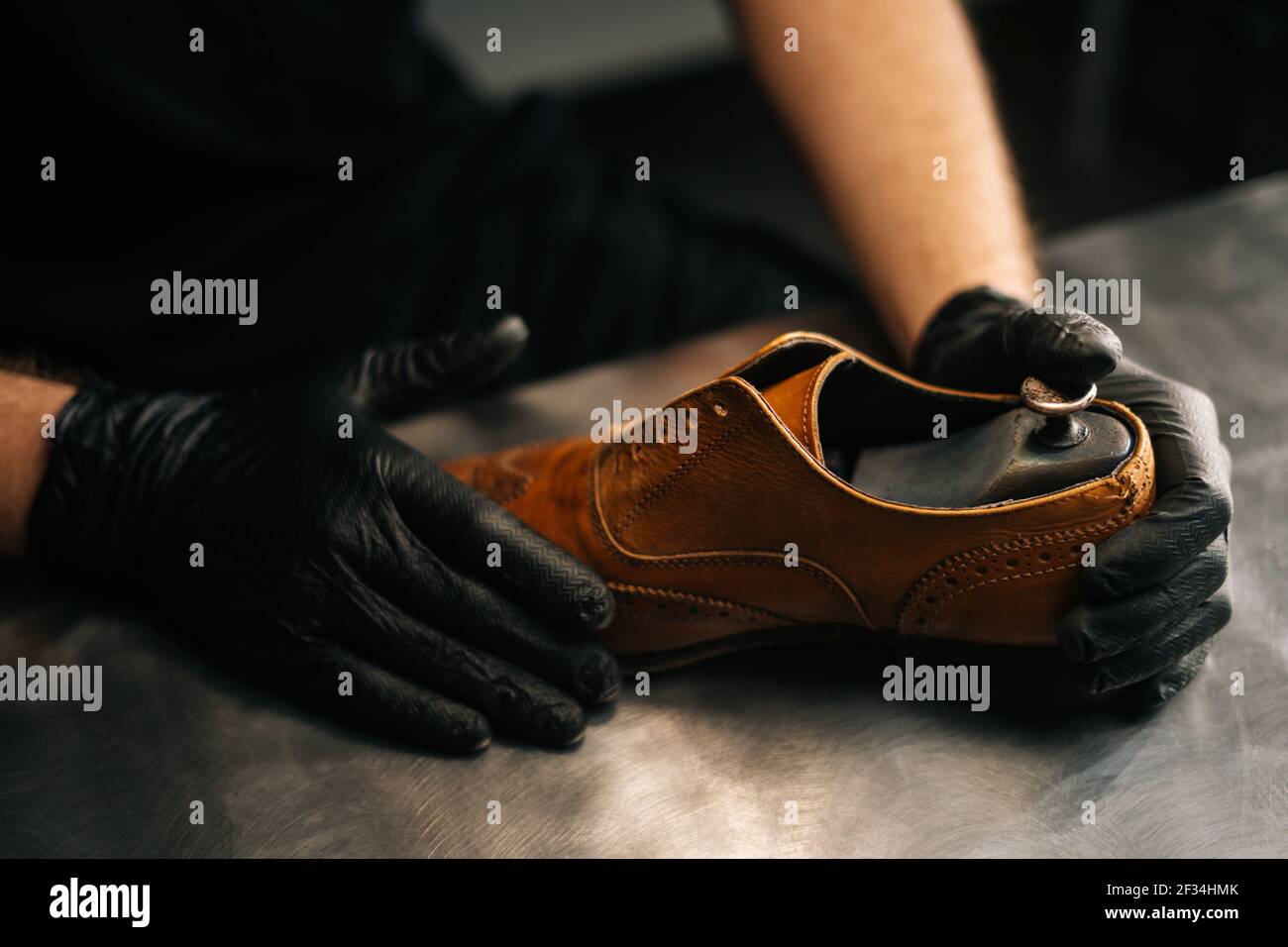 Close-up top view of hands of shoemaker shoemaker wearing black gloves ...
